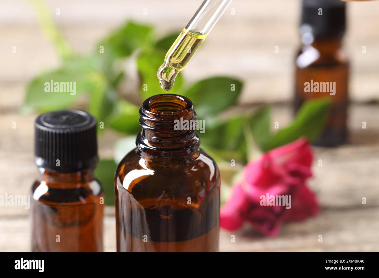 Essential oil dripping from pipette into bottle at table, closeup Stock ...