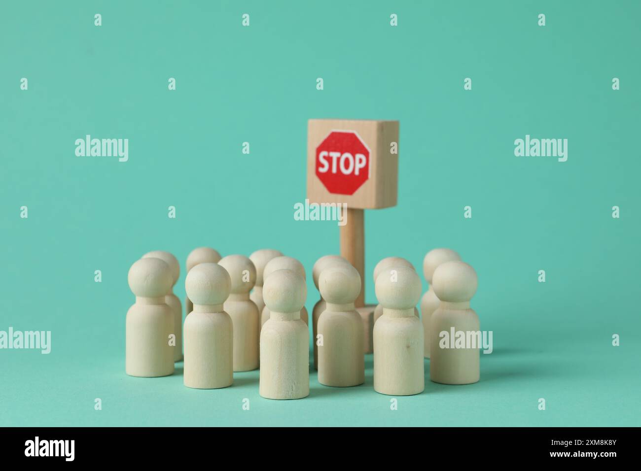 Road Stop sign blocking way for wooden human figures on turquoise ...