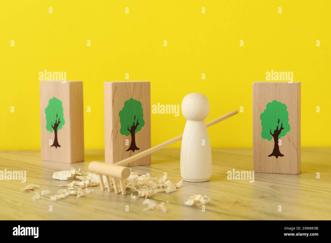 Wooden human figure with rake and sawdust among planks with drawn trees ...