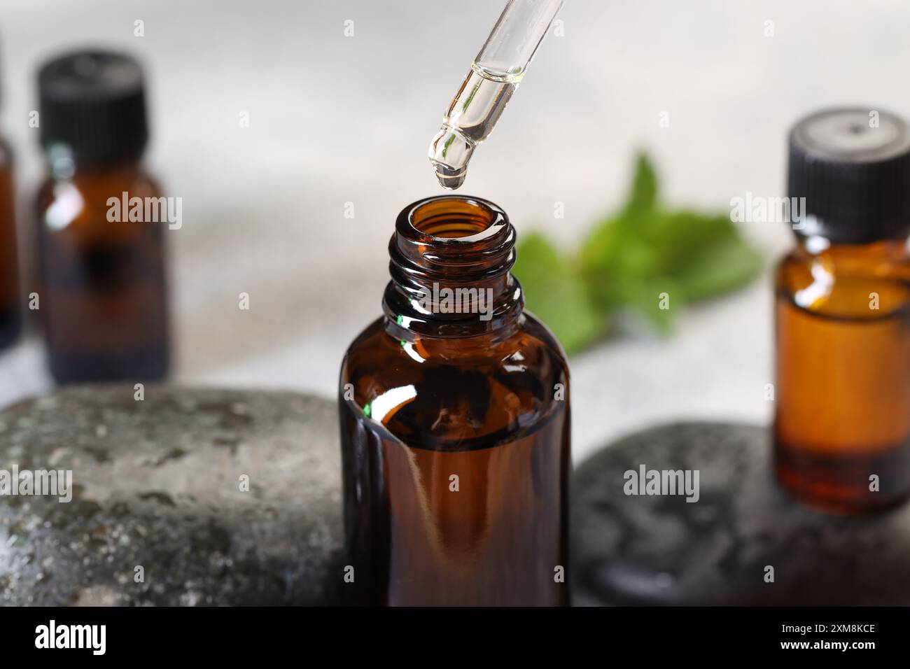 Essential oil dripping from pipette into bottle on table, closeup Stock ...