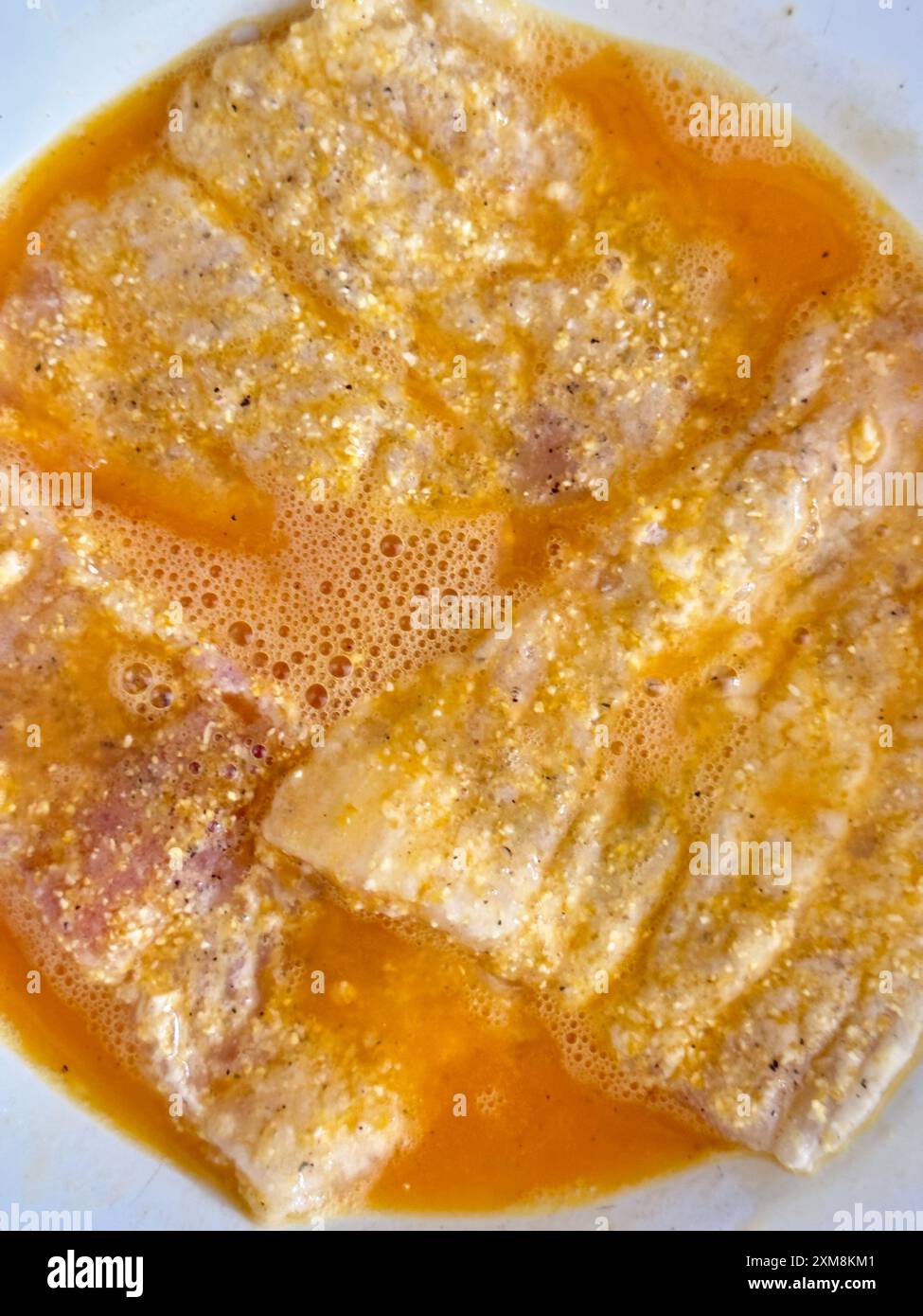 Raw fish fillets marinating in a seasoned liquid for cooking ...