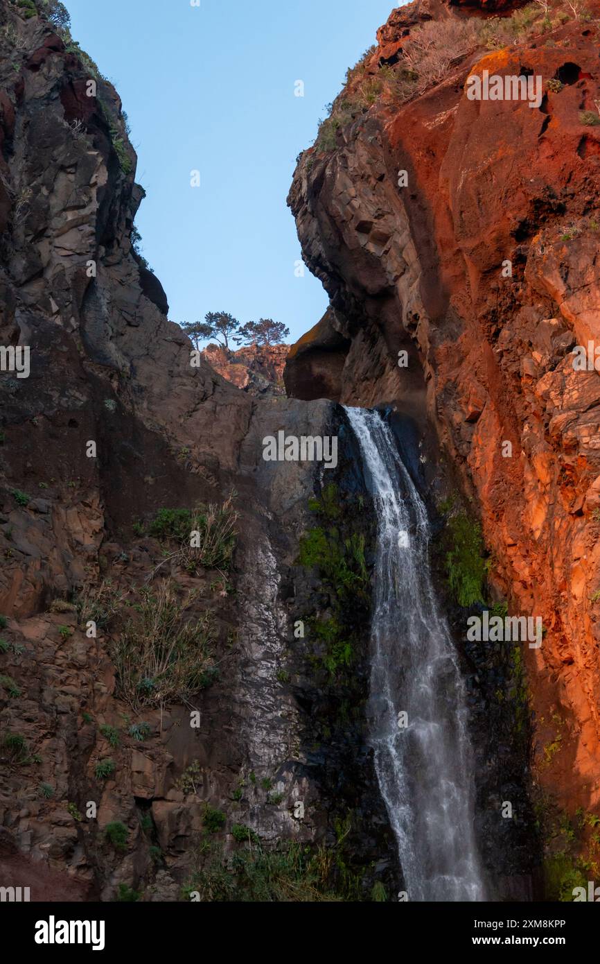 Orange color of a mountain during golden hour. Waterfall in a canyon ...