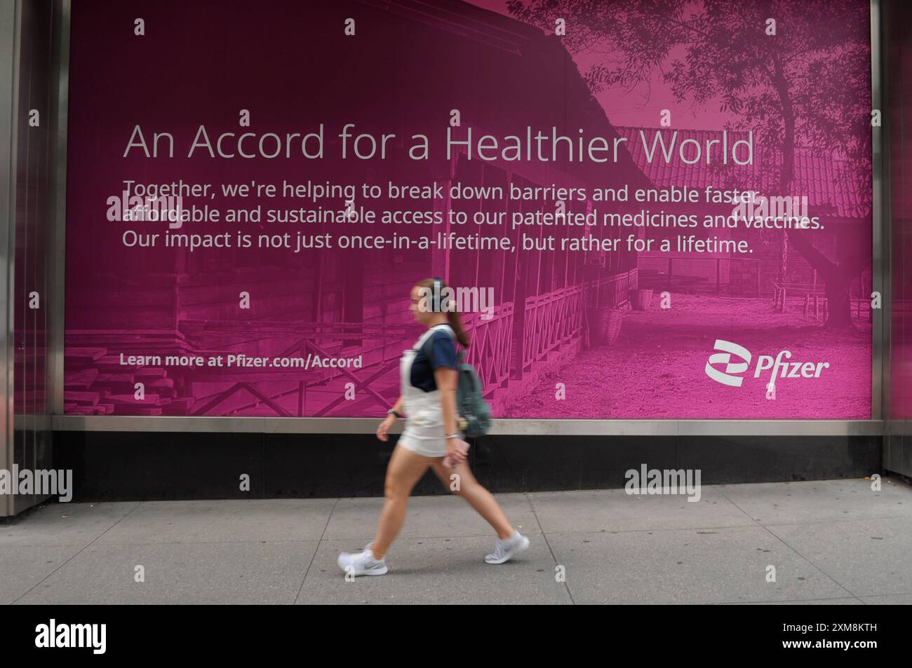 A person walks past a sign outside of the Pfizer world headquarters ...