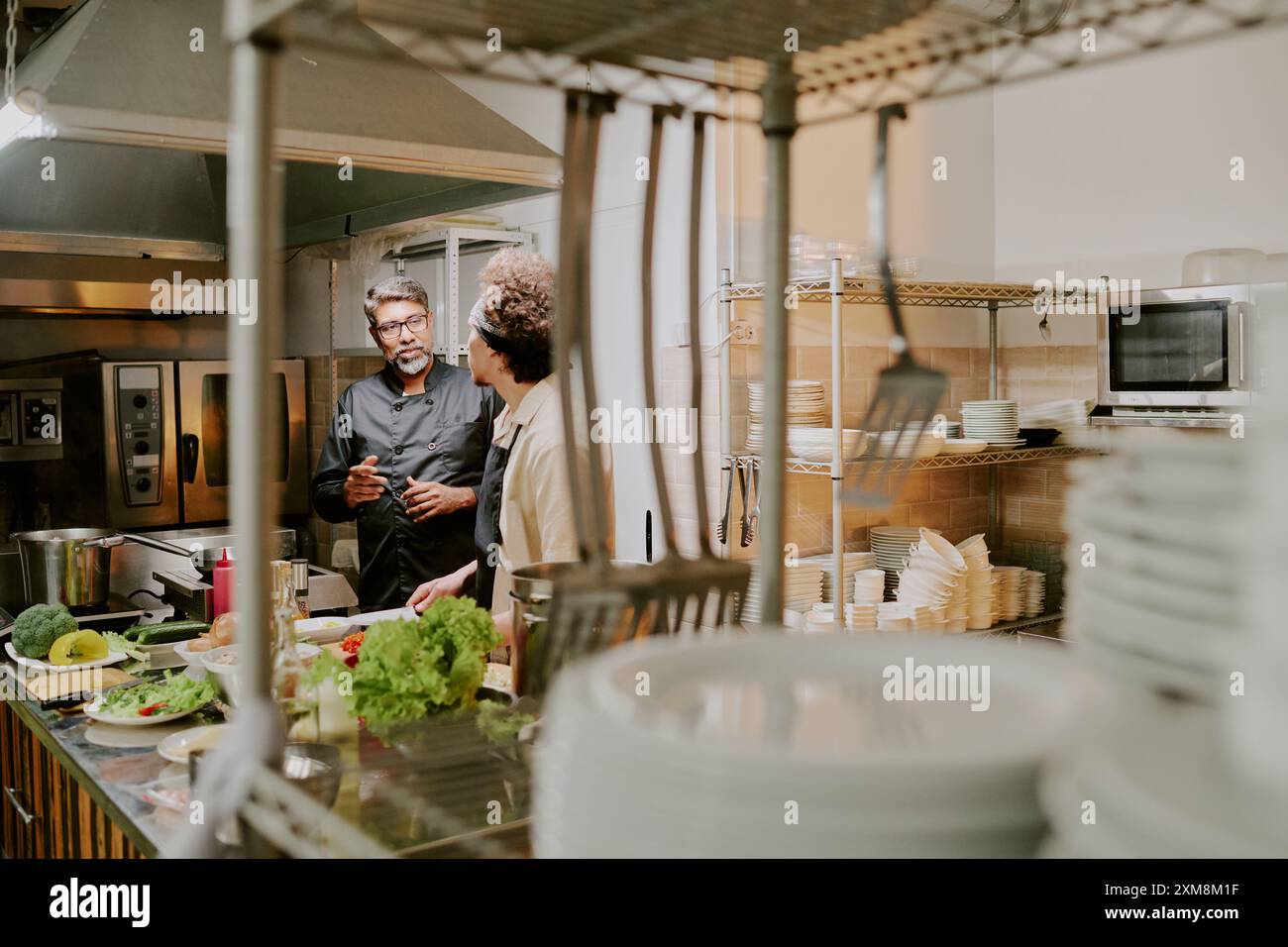 Two highly skilled cooks standing in center of restaurant kitchen and ...
