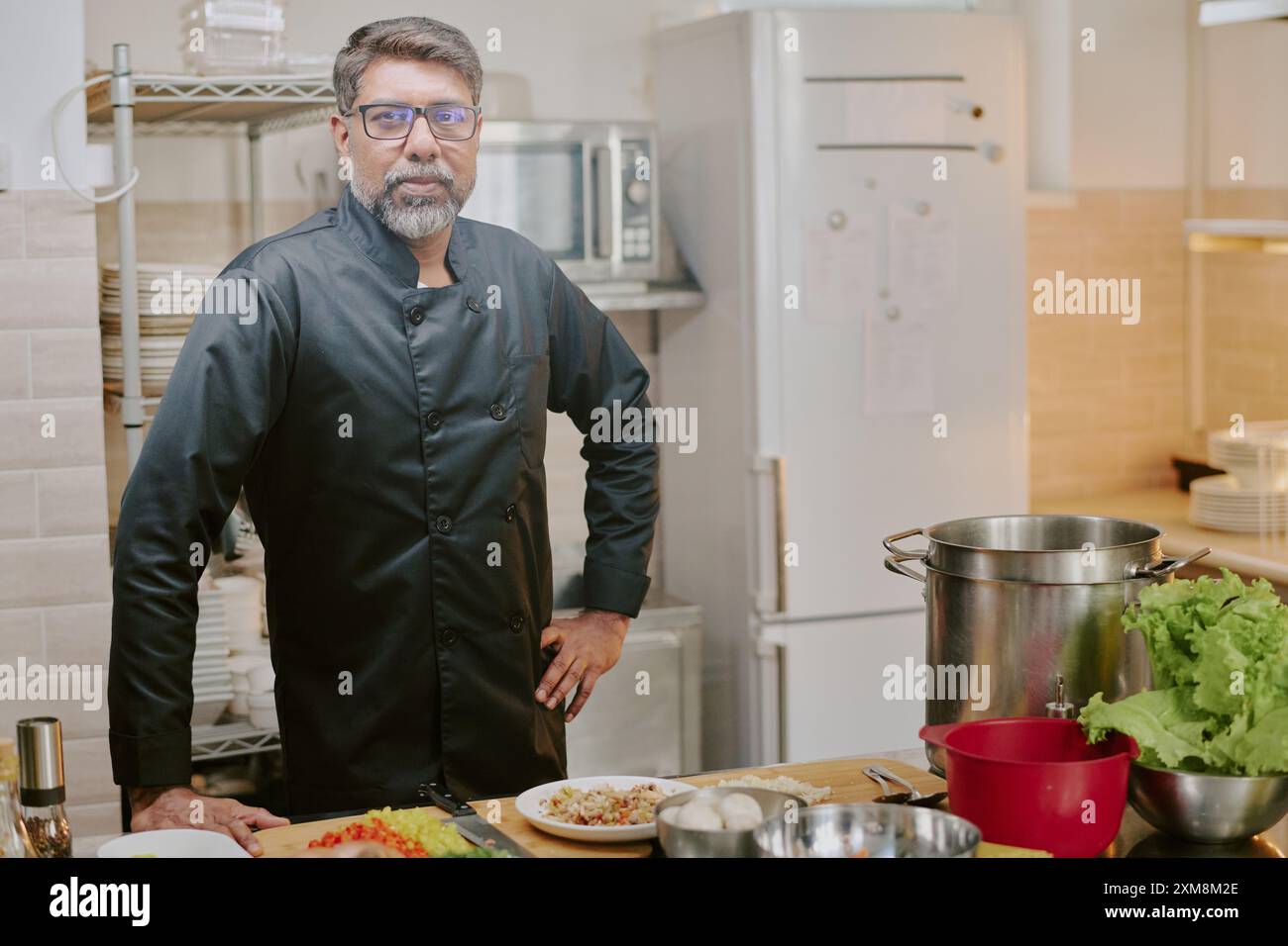 Middle aged Indian chef with gray beard looking directly at camera ...