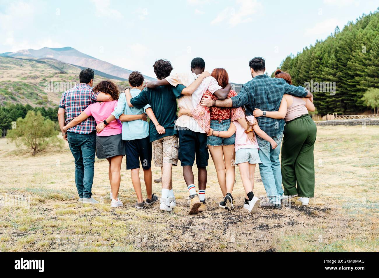 Rear view of a diverse group of young friends hugging and walking ...