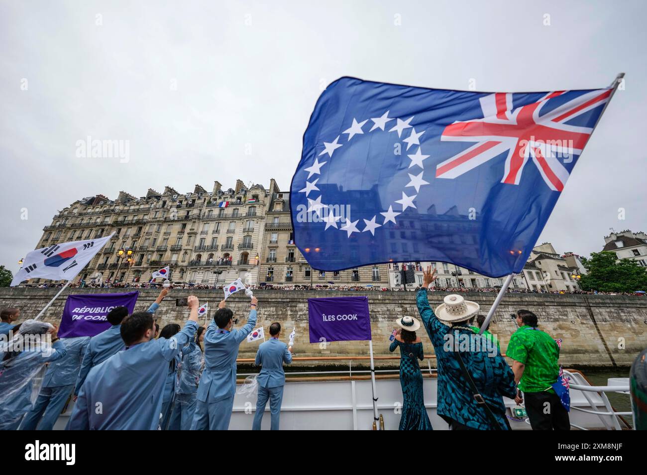 Team South Korea and Team Cook Islands wave their flags from a boat in ...