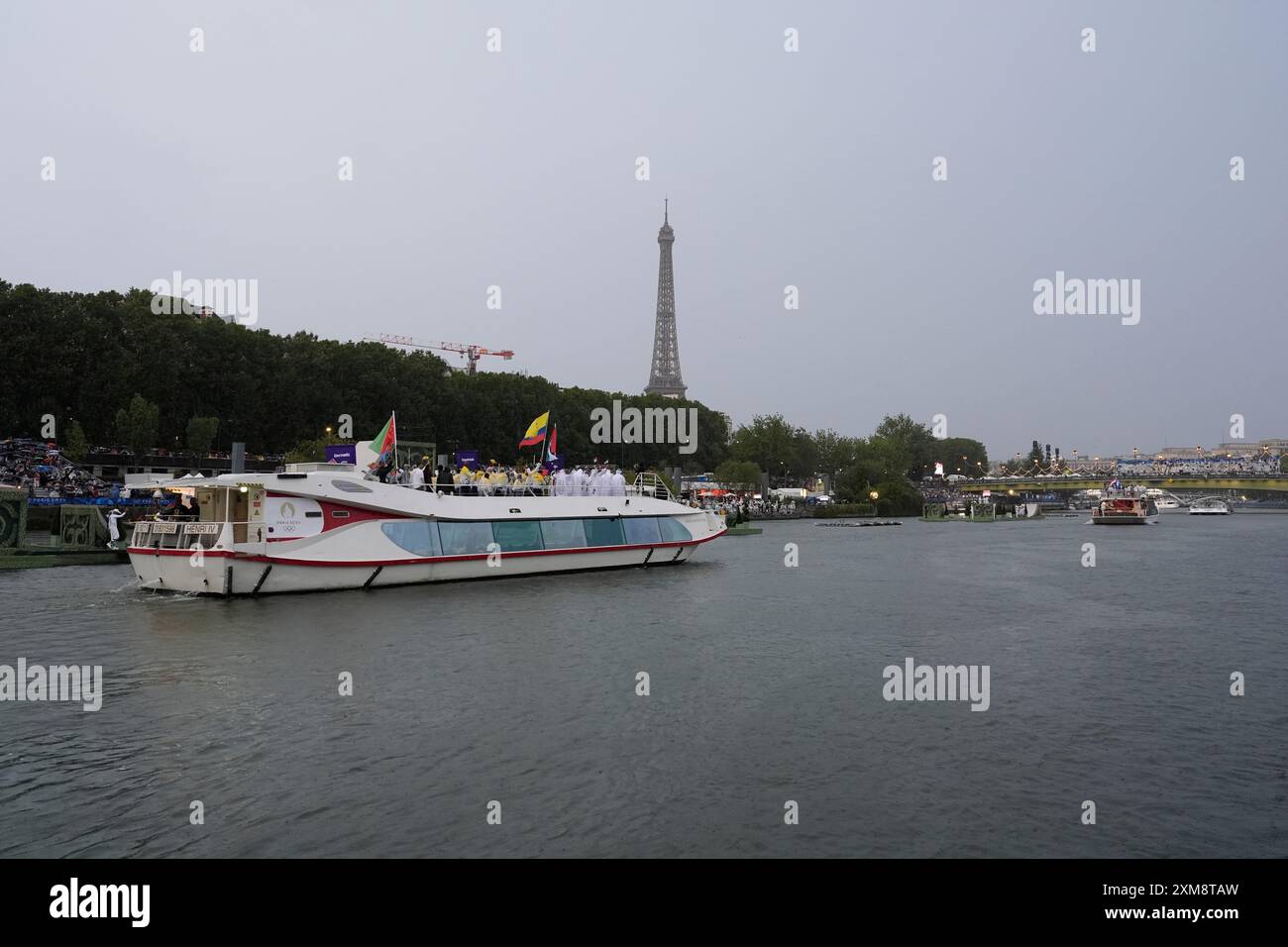 A parade of boats moves down the Seine River as the Eiffel Tower is ...