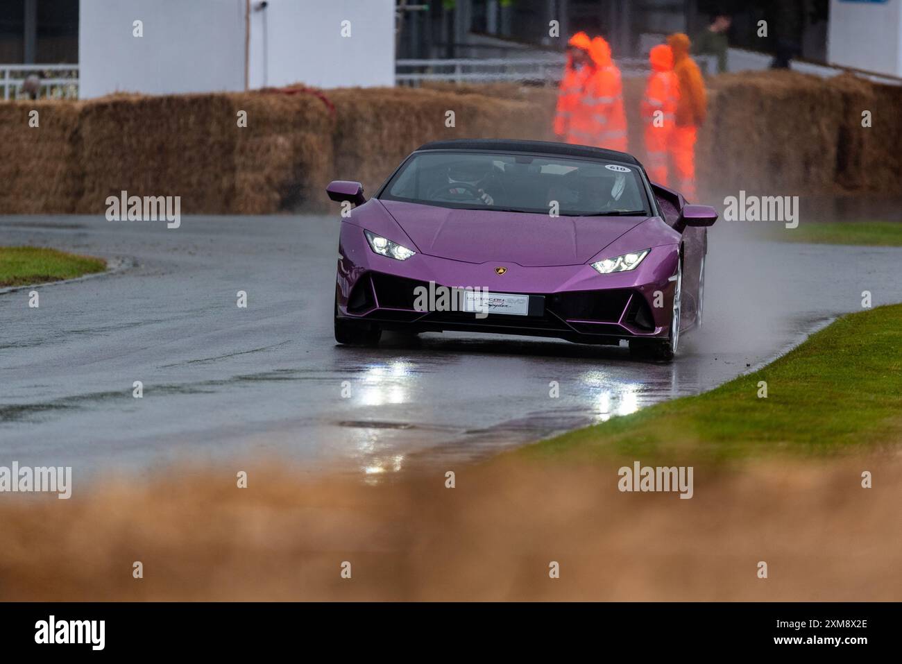 2024 Lamborghini Huracán EVO Spyder sports car driving up the wet hillclimb track in heavy rain ...