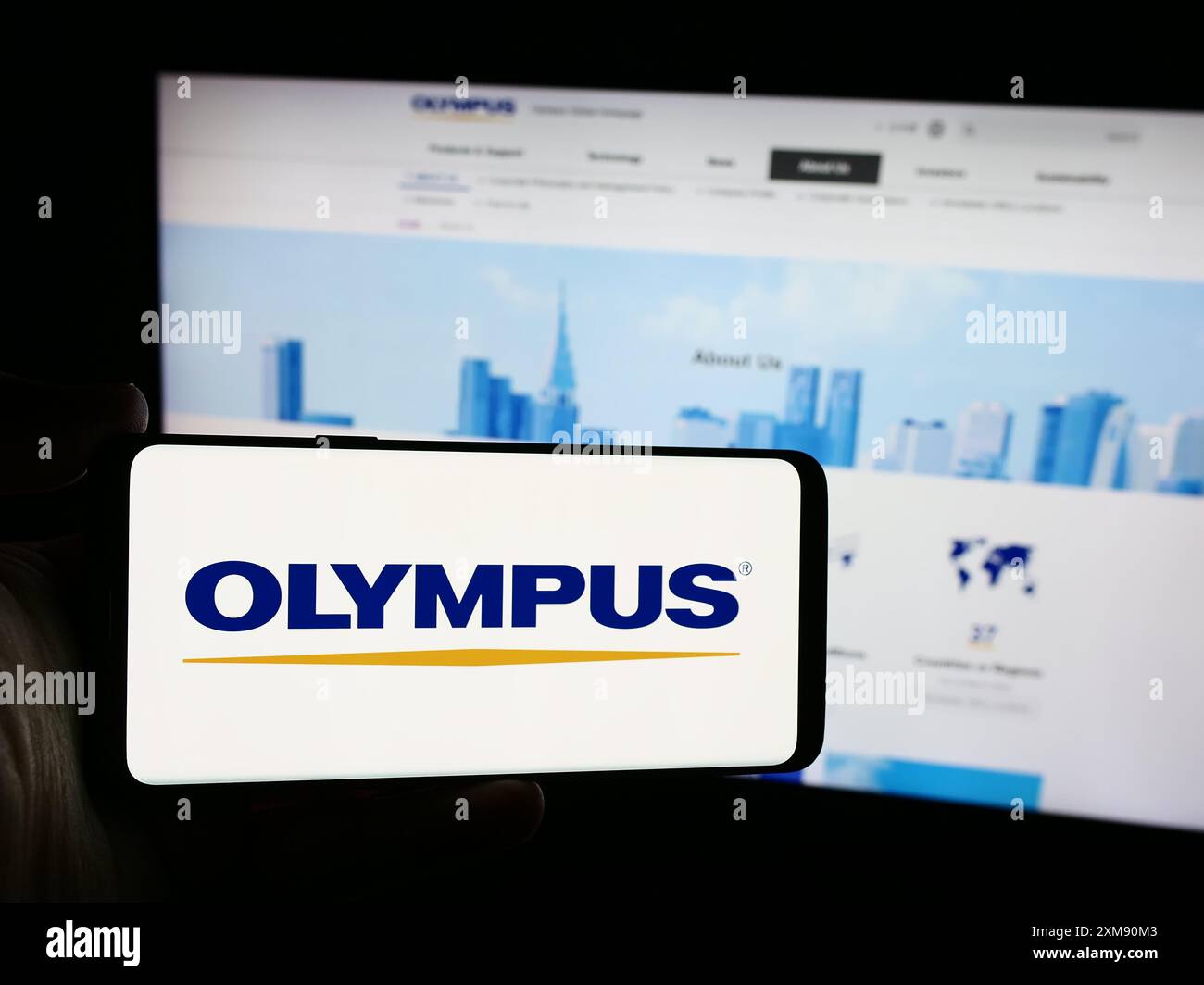 Person holding smartphone with logo of Japanese optics company Olympus ...