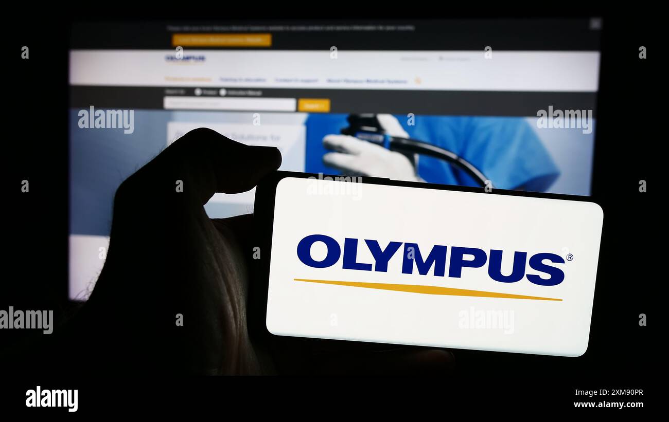 Person holding mobile phone with logo of Japanese optics company ...