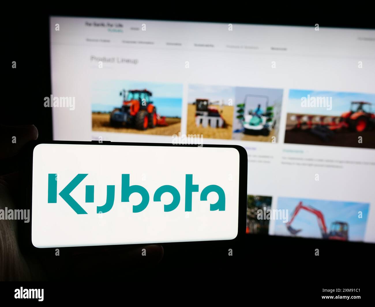 Person holding mobile phone with logo of Japanese heavy equipment ...