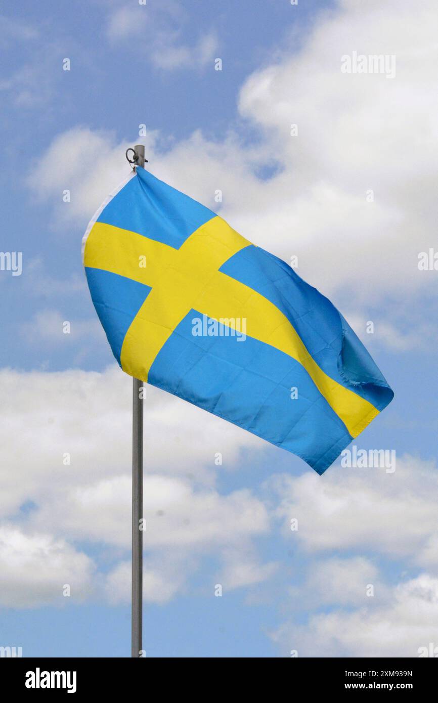 The national flag of Sweden flies up a flagpole on a beautiful summer ...