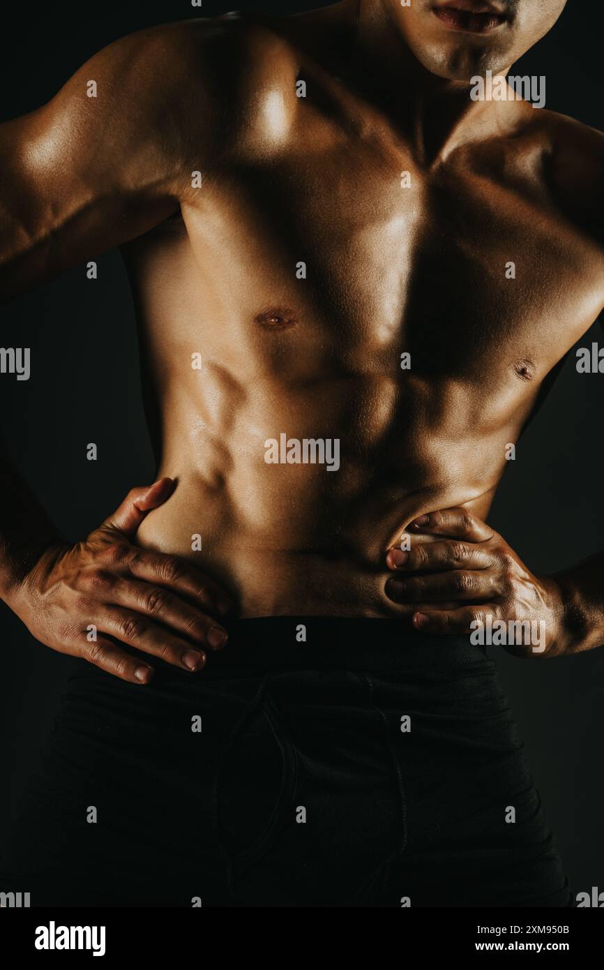 Fit muscular man showing abs and toned body in dark lighting Stock ...