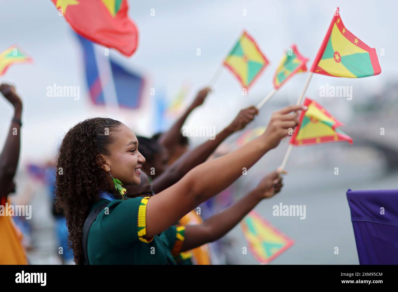 Athletes from Grenada wave flags on a boat along the River Seine during ...