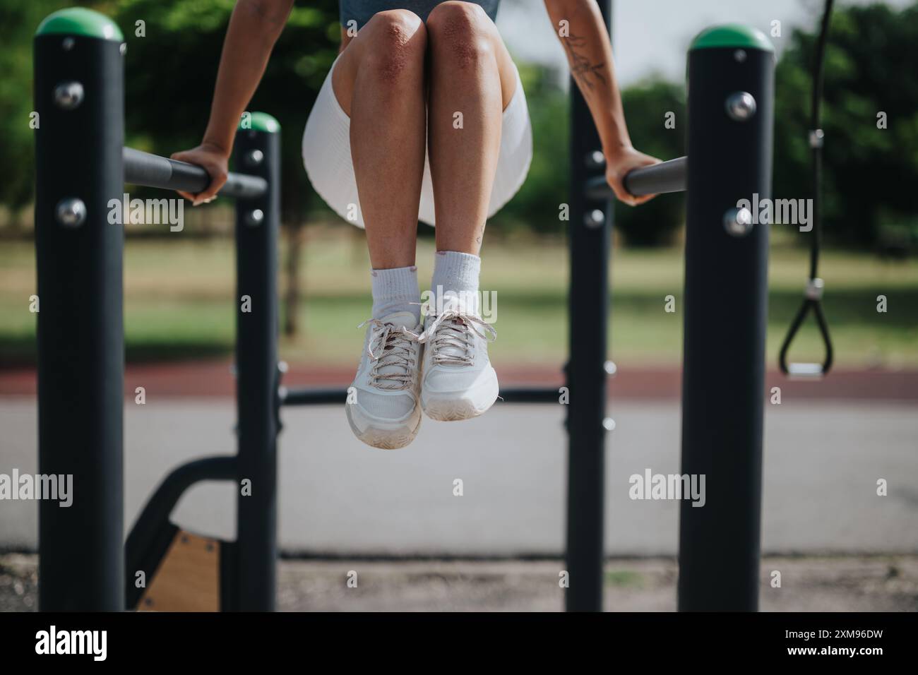 Person performing calisthenics workout on parallel bars in sunny park ...