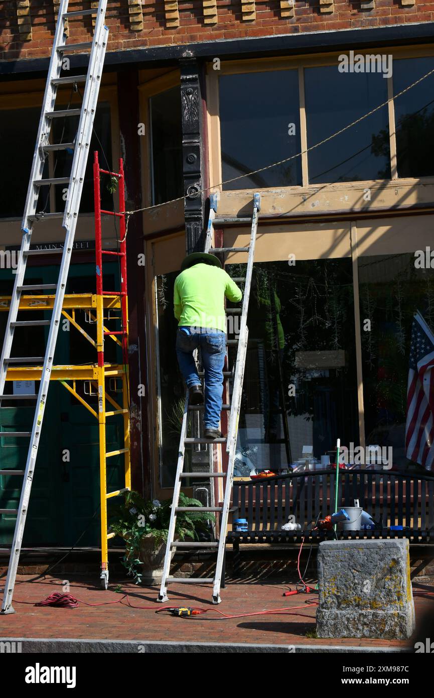 Man descends ladder, propped against historic building, on Main Street, Jonesborough, Tennessee ...