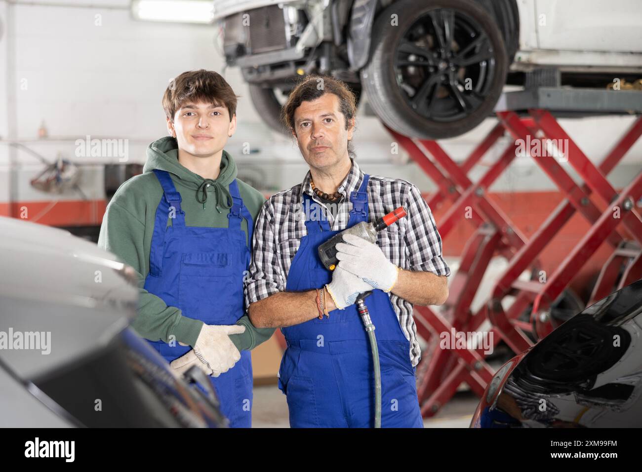 Seasoned auto repair service owner posing with young mechanic in ...