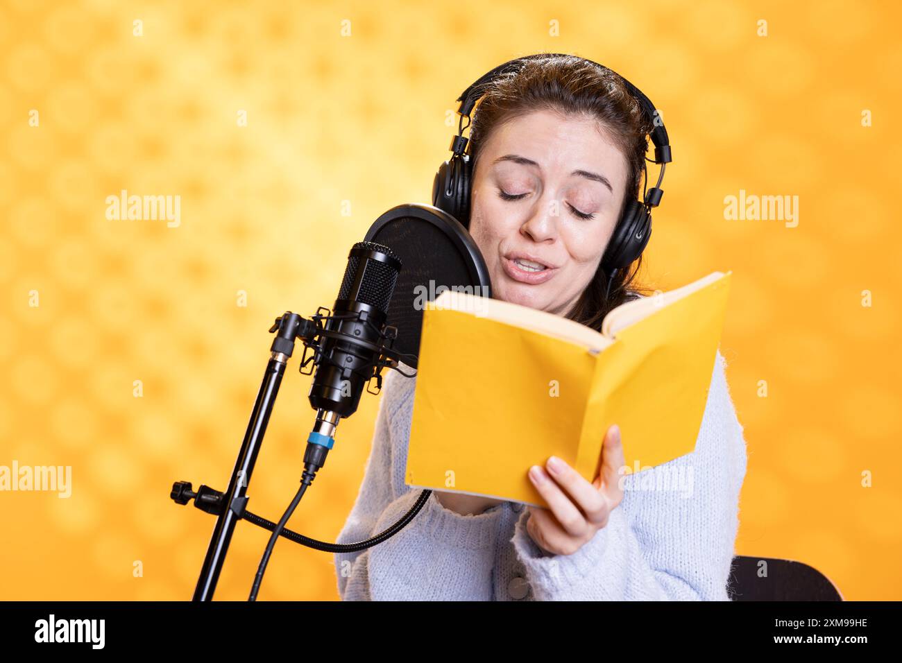 Voice actor reading book, recording audiobook using microphone and ...