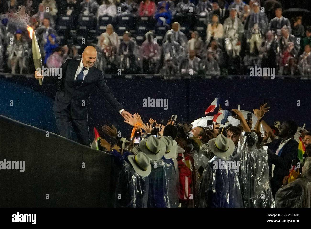 French soccer star Zinedine Zidane carries the torch during the opening ...