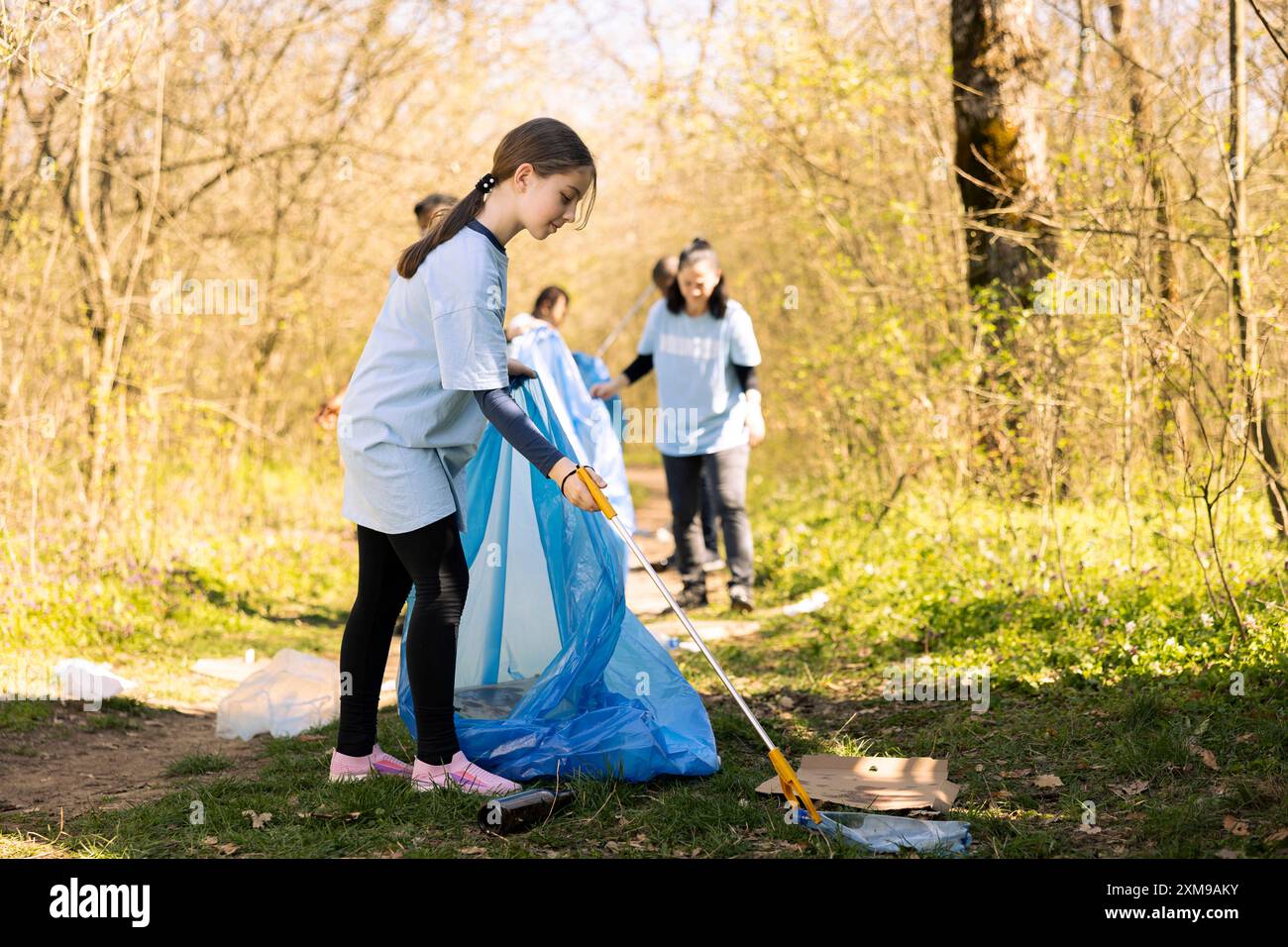 Little child activist collecting rubbish in blue garbage disposal bags ...