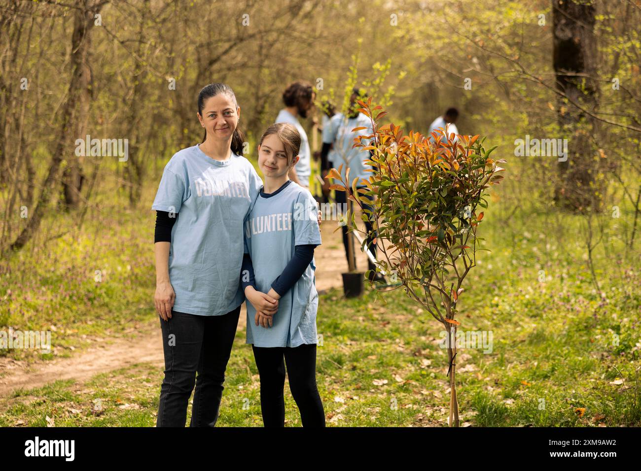 Portrait of mom and her daughter volunteering to plant trees in the ...