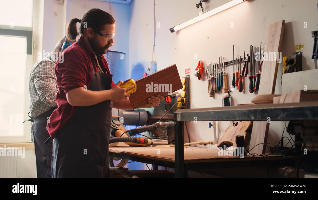 Artisan next to coworker using sanding block to remove imperfections on ...