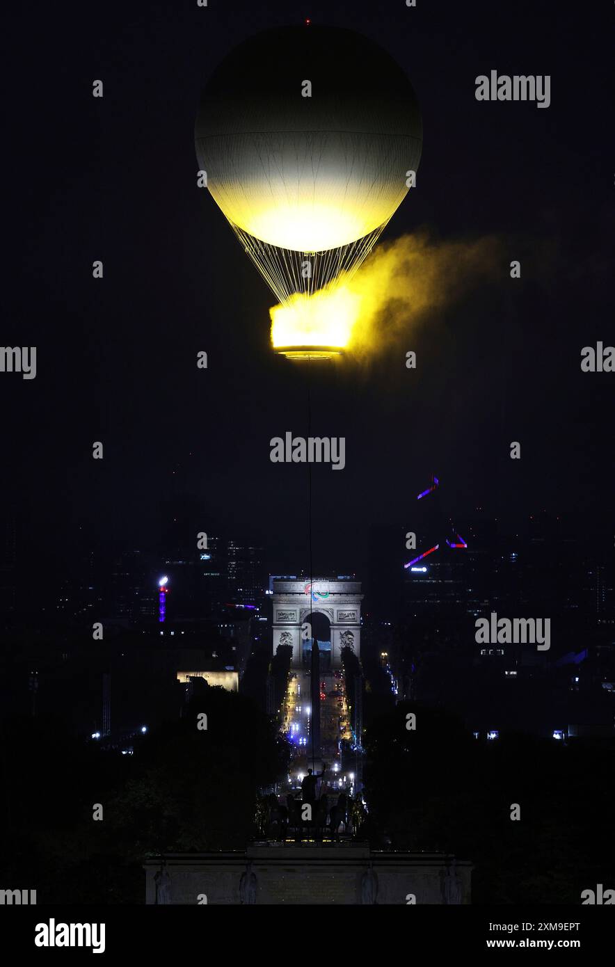 A balloon carrying the Olympic Cauldron rises over the Arc de Triomphe ...