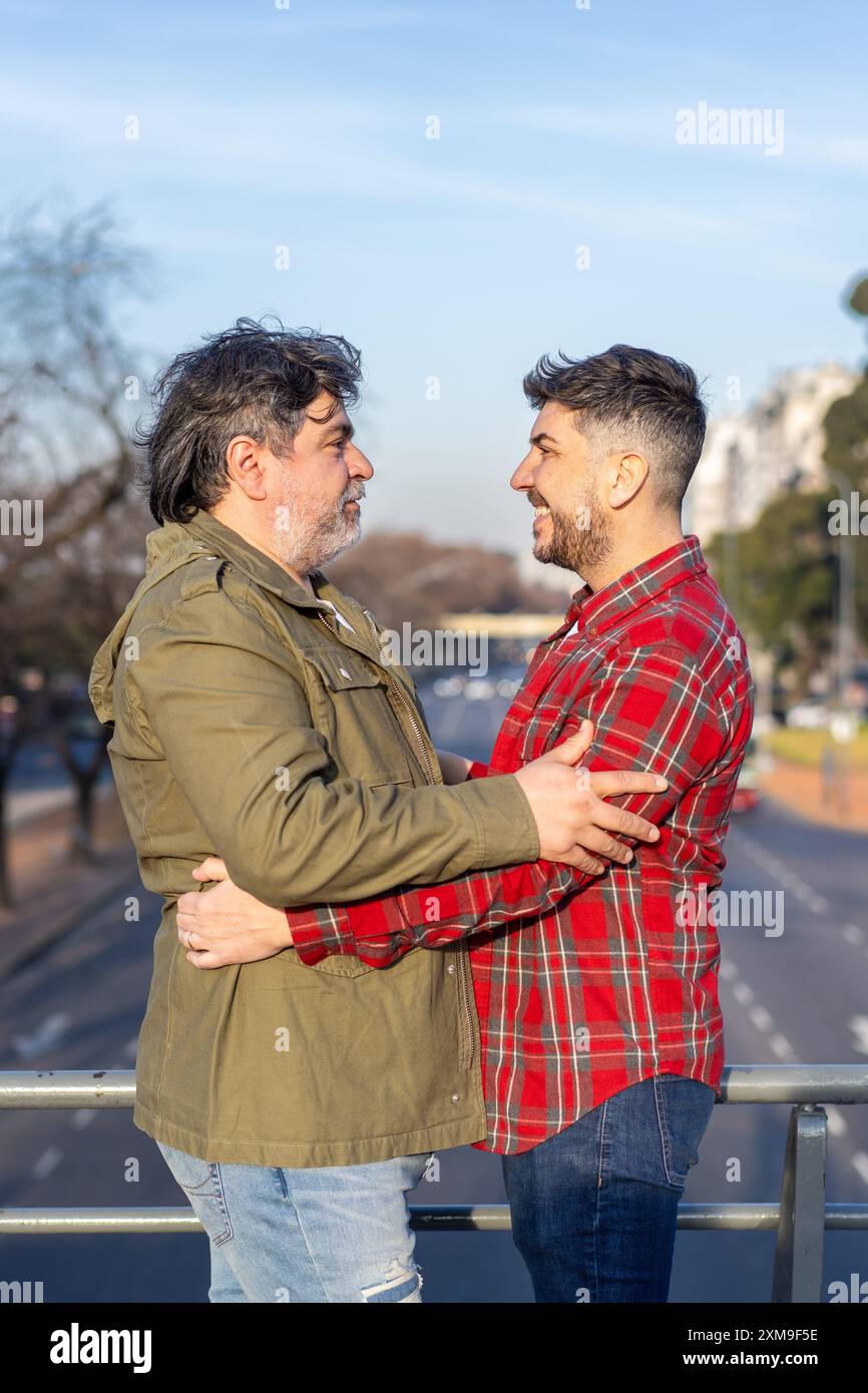 Mid-adult gay couple cuddling outdoors. Vertical shot Stock Photo - Alamy