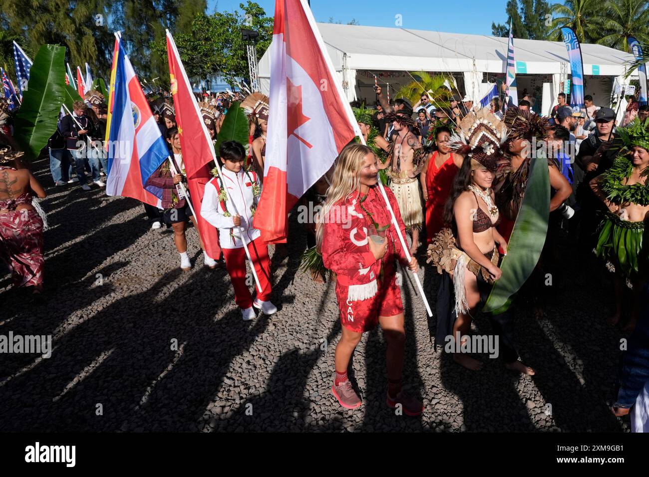 Surfer Sanoa Dempfle-Olin, of Canada, holds the flag as she arrives ...