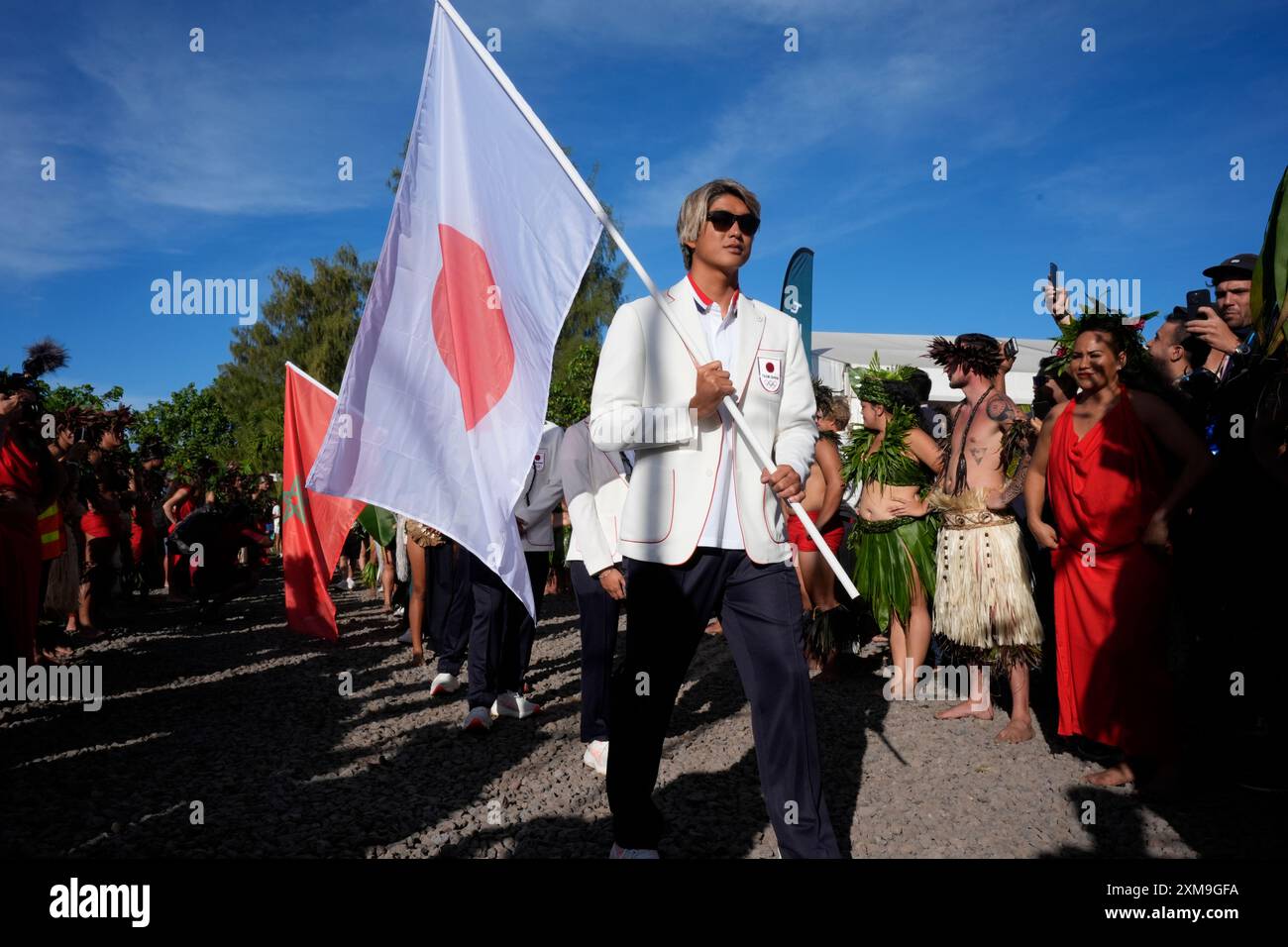 Kanoa Igarashi, of Japan, holds the flag during an opening ceremony for ...