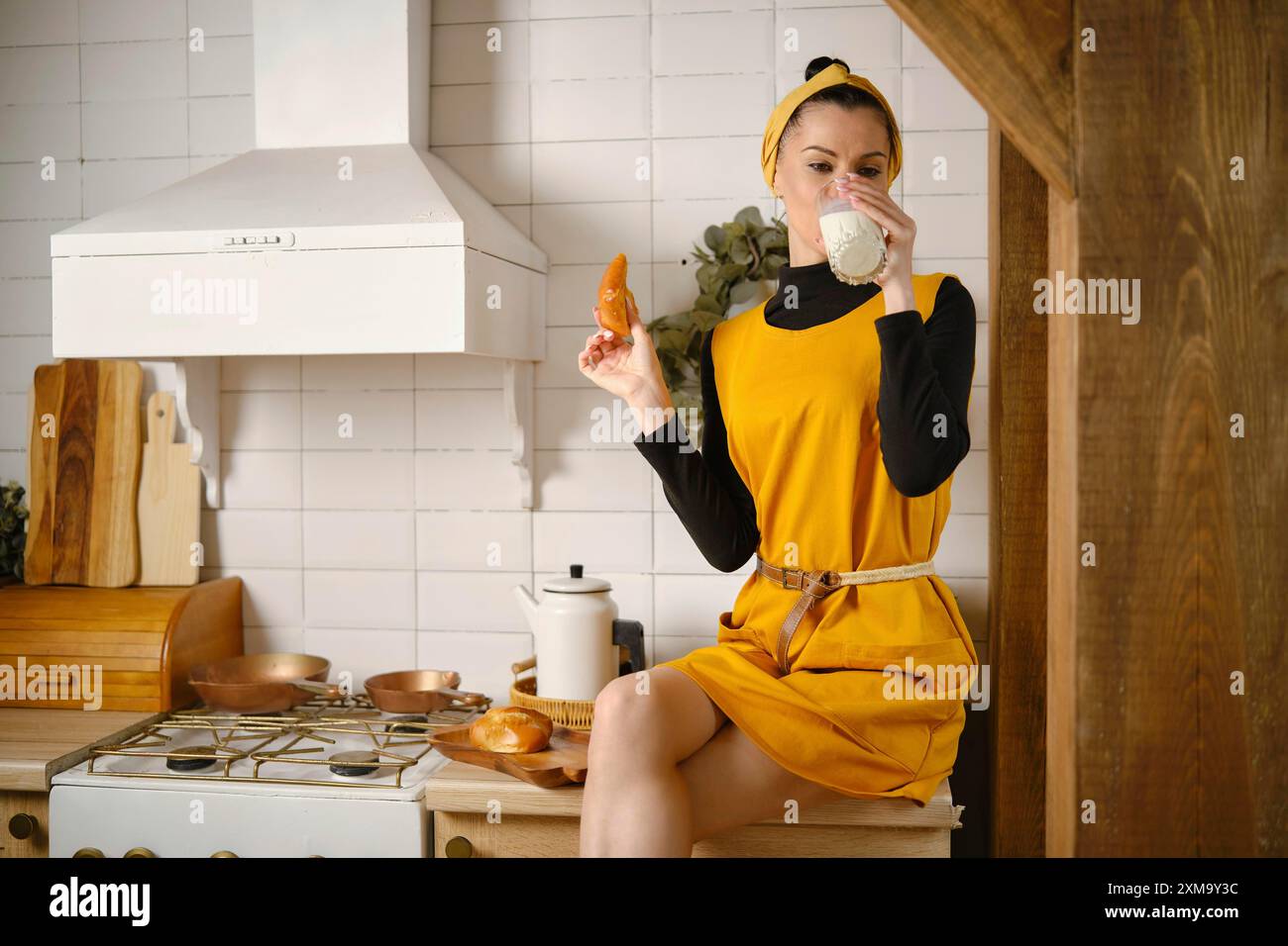 A woman in yellow sundress drinks a glass of milk while eating an apple ...