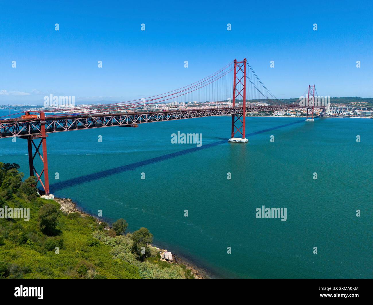 A large red bridge stretches across a wide expanse of water under a ...