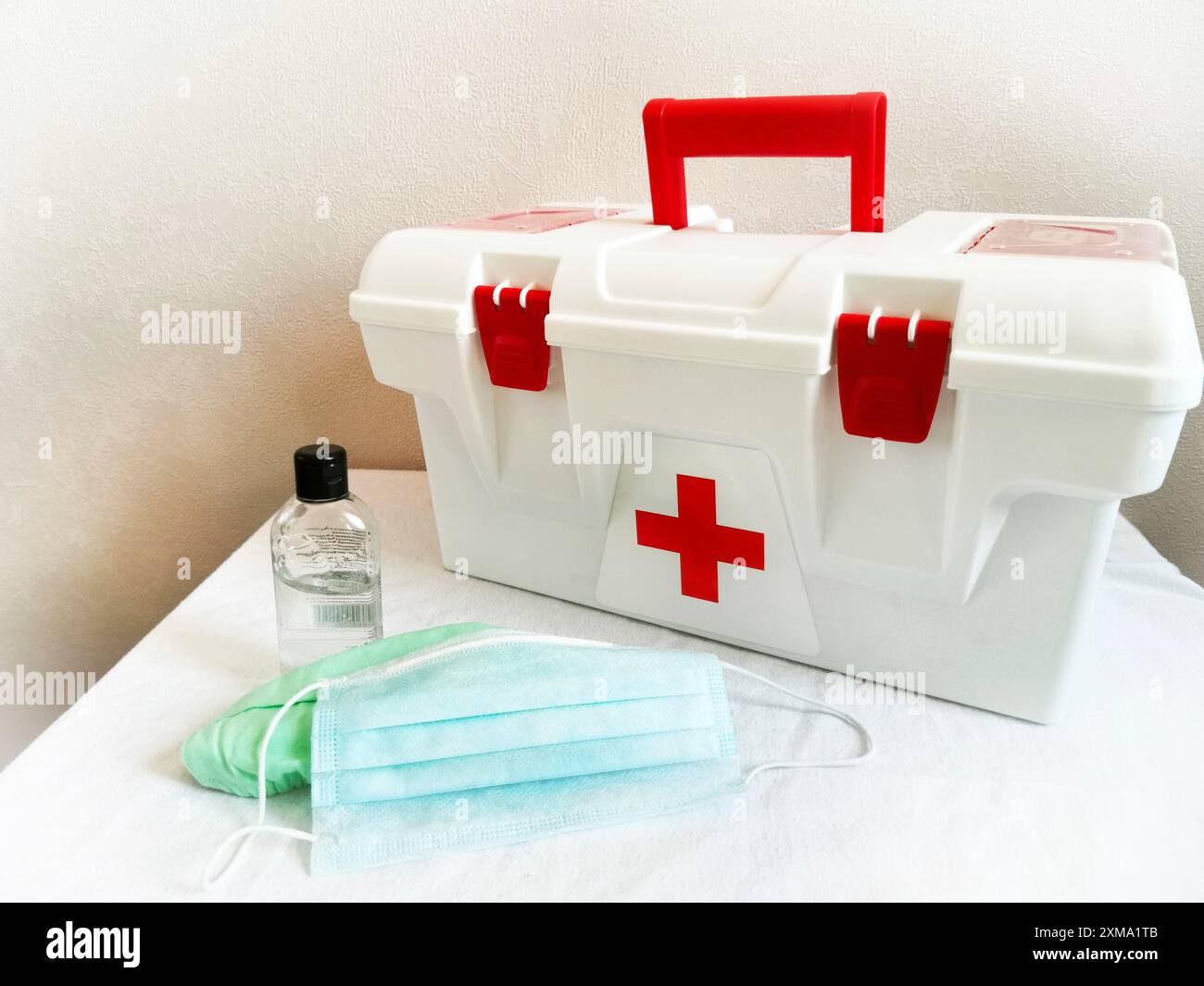 First aid kit with a red cross, face masks, and hand sanitizer on a ...