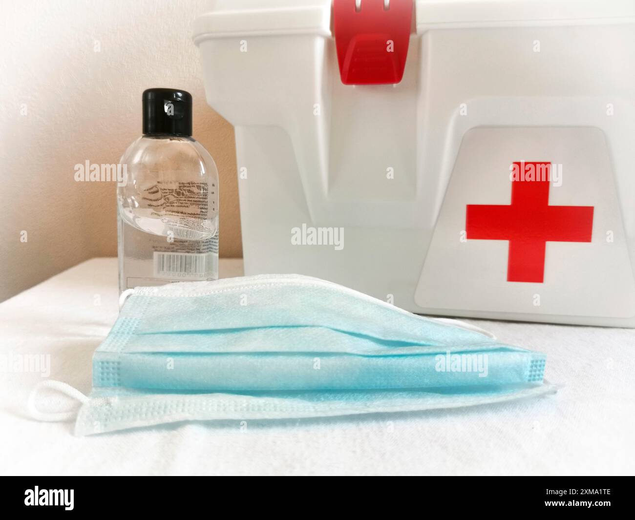 First aid kit with red cross, hand sanitizer, and blue face mask on ...