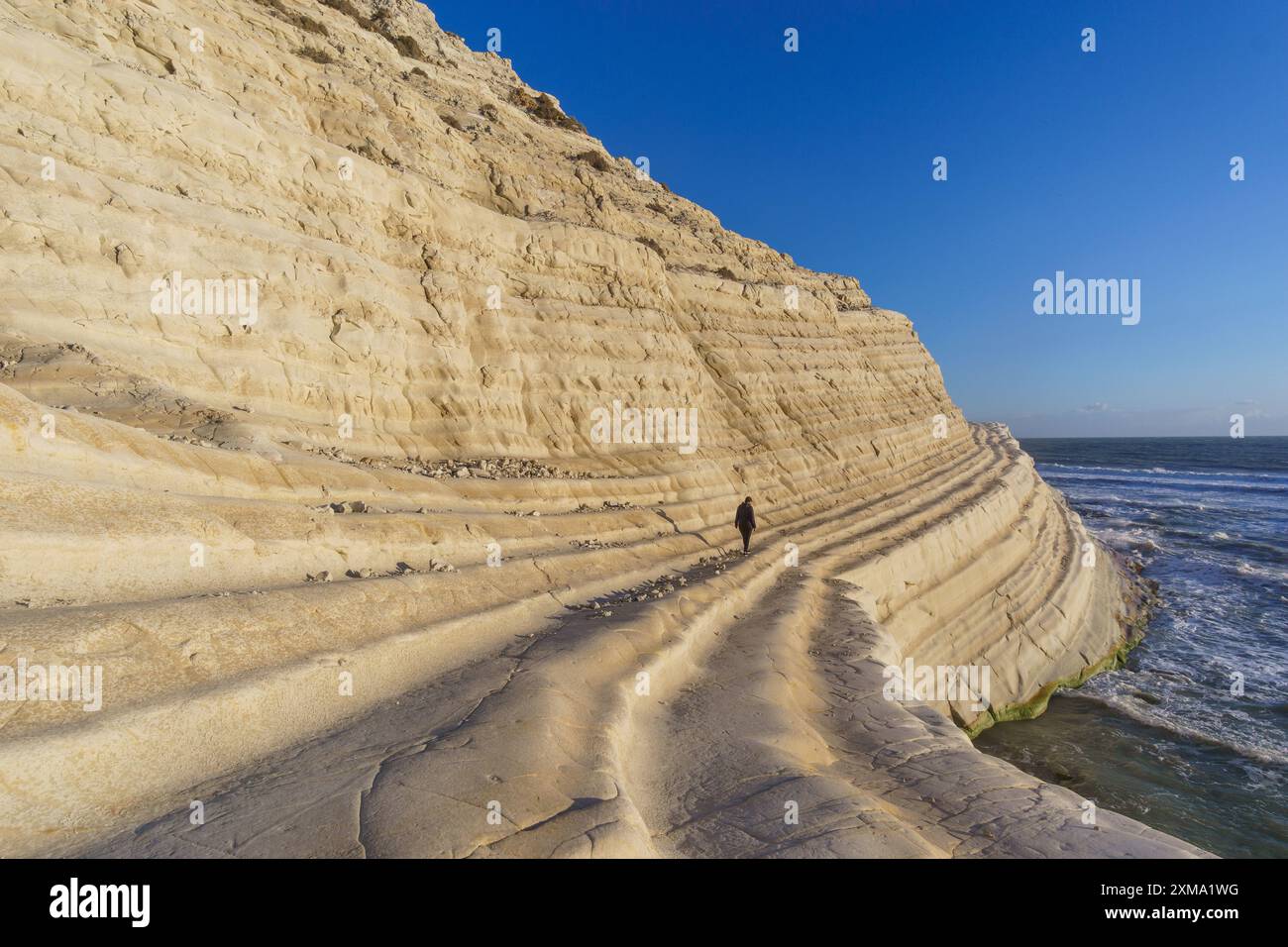 Tourist walking on rock cliff Stairs of the Turks or Scala dei Turchi ...