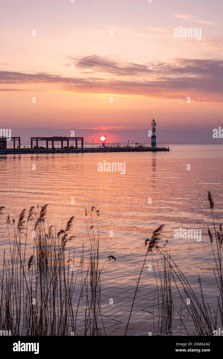 Sunrise on the shore and harbour of a lake in summer. Colourful sky ...