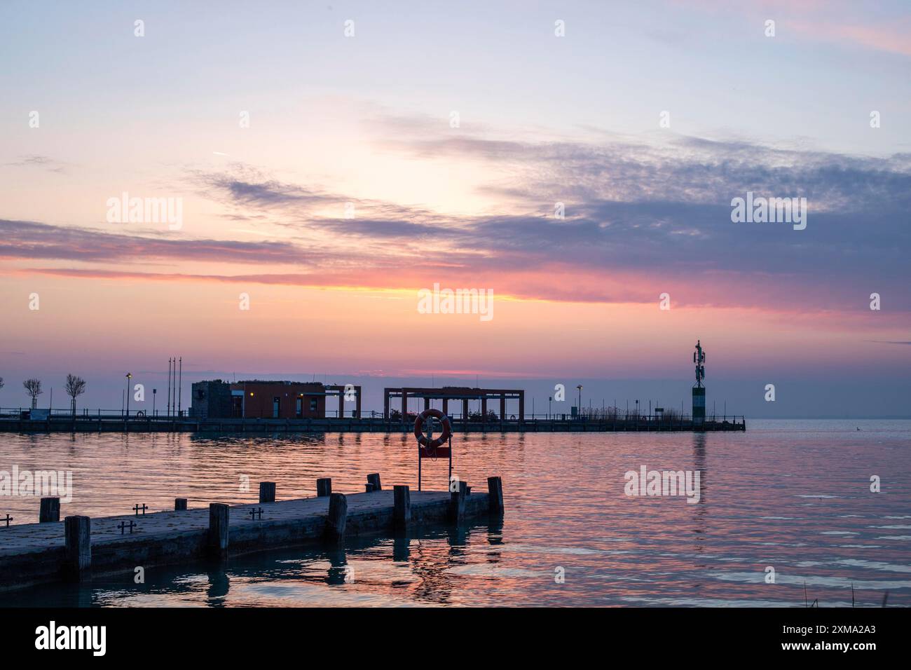 Sunrise on the shore and harbour of a lake in summer. Colourful sky ...