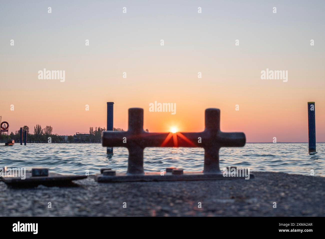 Sunrise on the shore and harbour of a lake in summer. Colourful sky ...