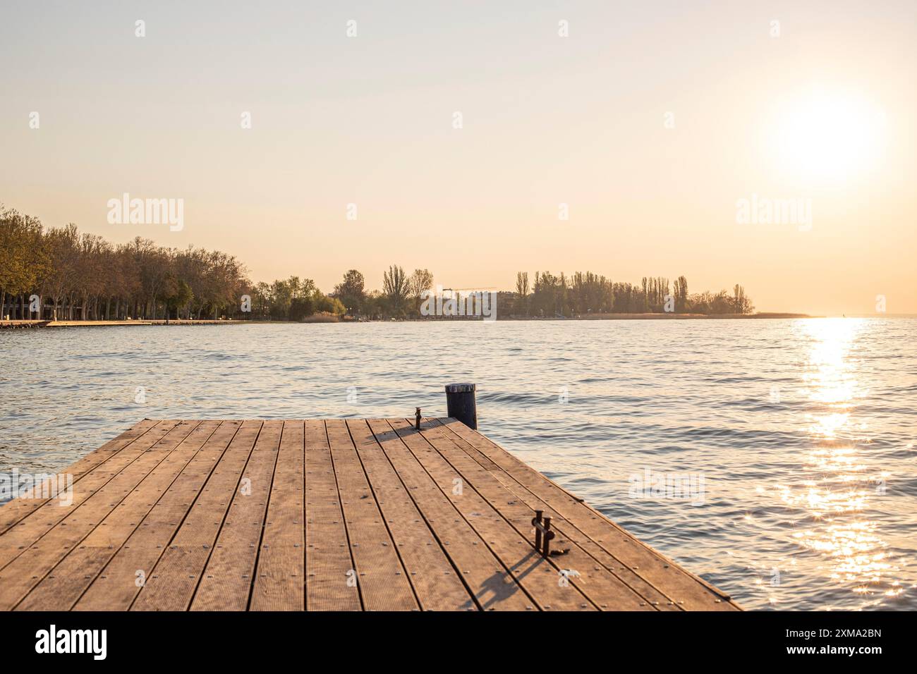 Sunrise on the shore and harbour of a lake in summer. Colourful sky ...