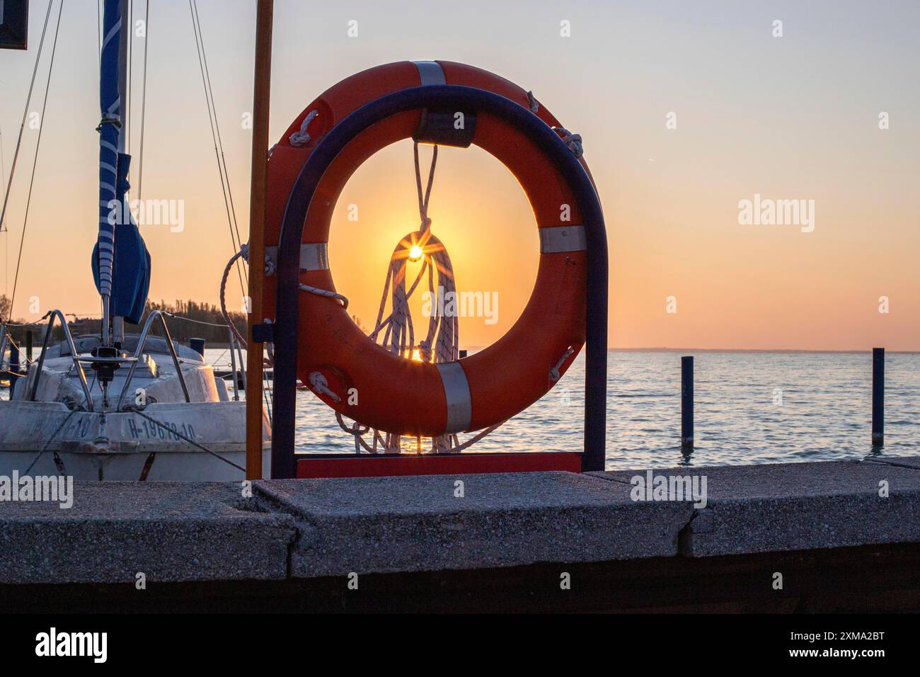 Sunrise on the shore and harbour of a lake in summer. Colourful sky ...
