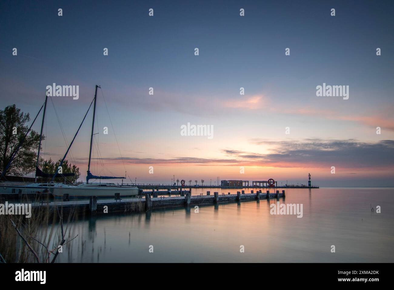 Sunrise on the shore and harbour of a lake in summer. Colourful sky ...