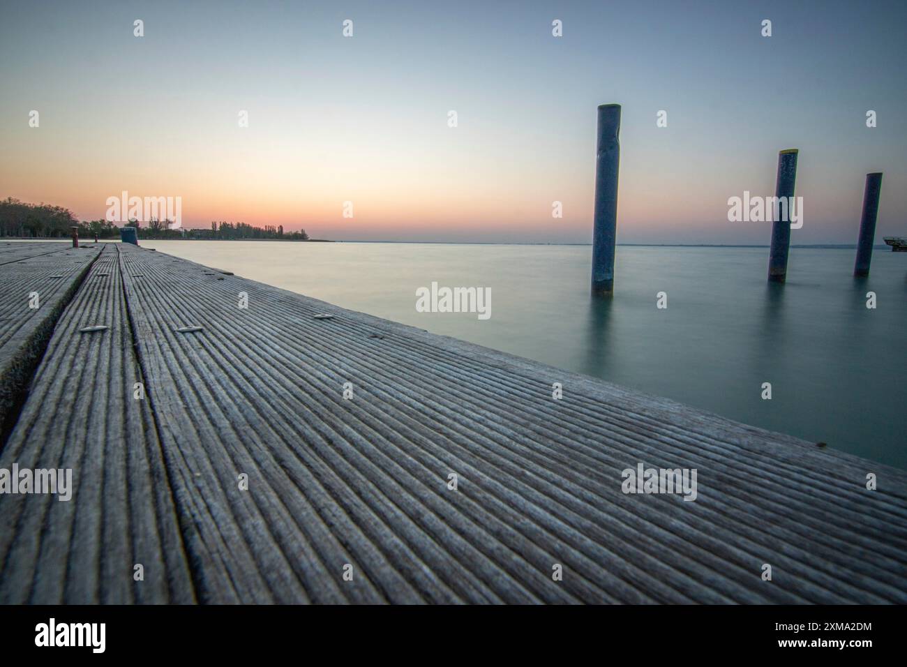 Sunrise on the shore and harbour of a lake in summer. Colourful sky ...