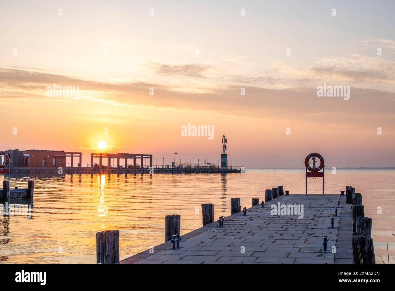 Sunrise on the shore and harbour of a lake in summer. Colourful sky ...