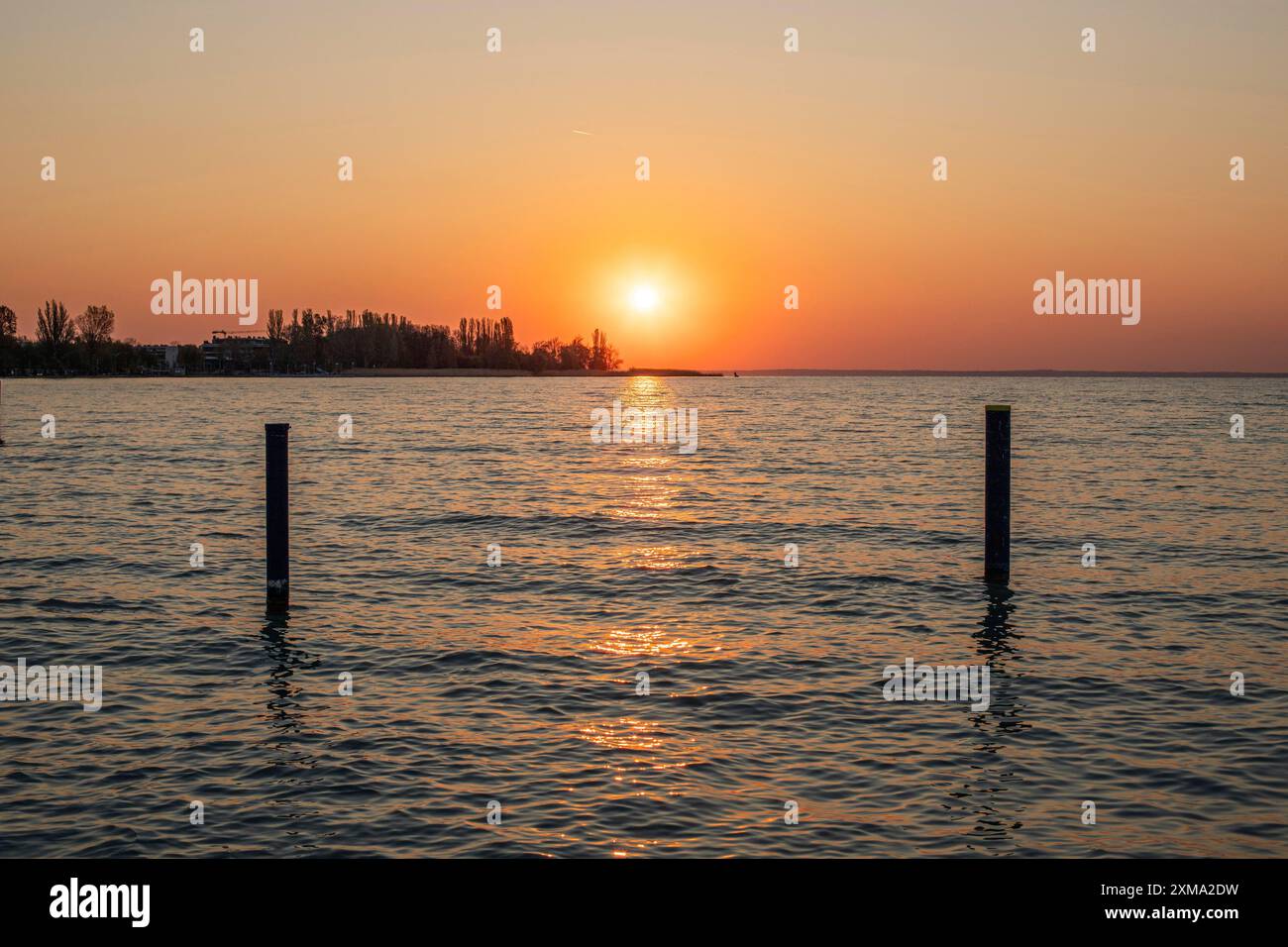 Sunrise on the shore and harbour of a lake in summer. Colourful sky ...