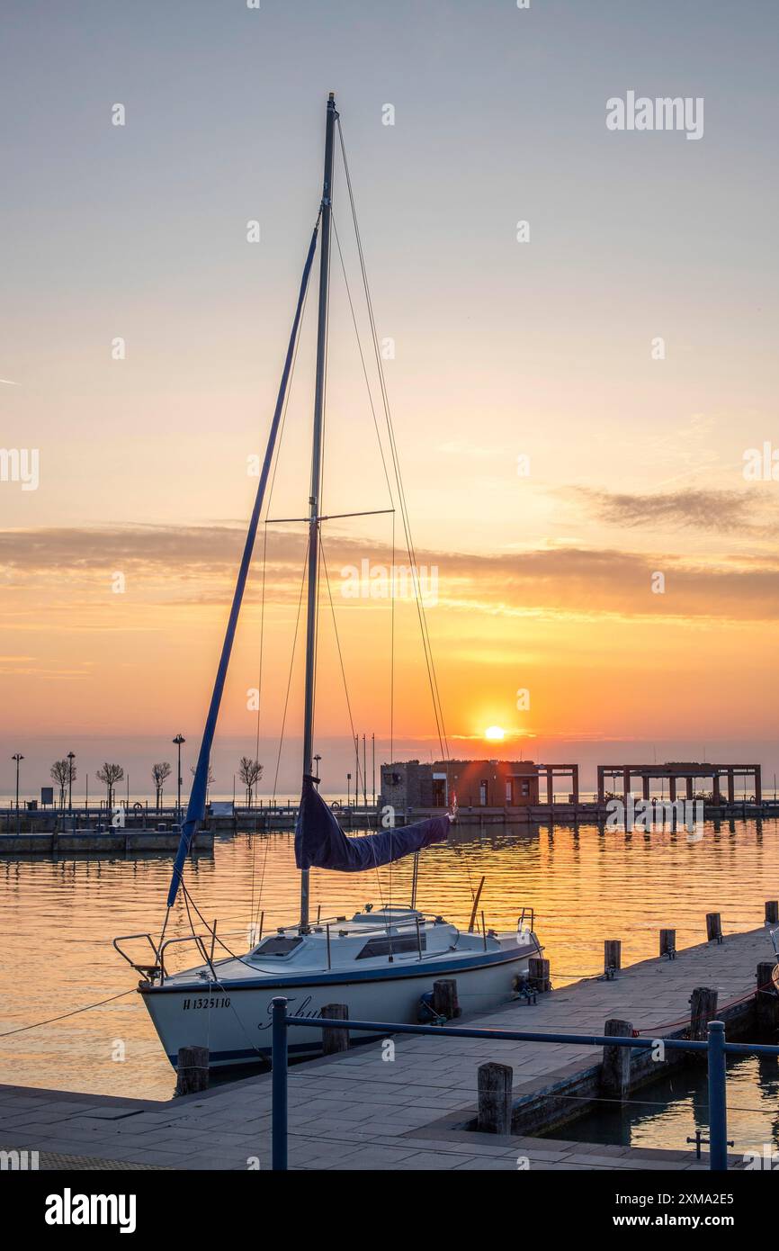 Sunrise on the shore and harbour of a lake in summer. Colourful sky ...