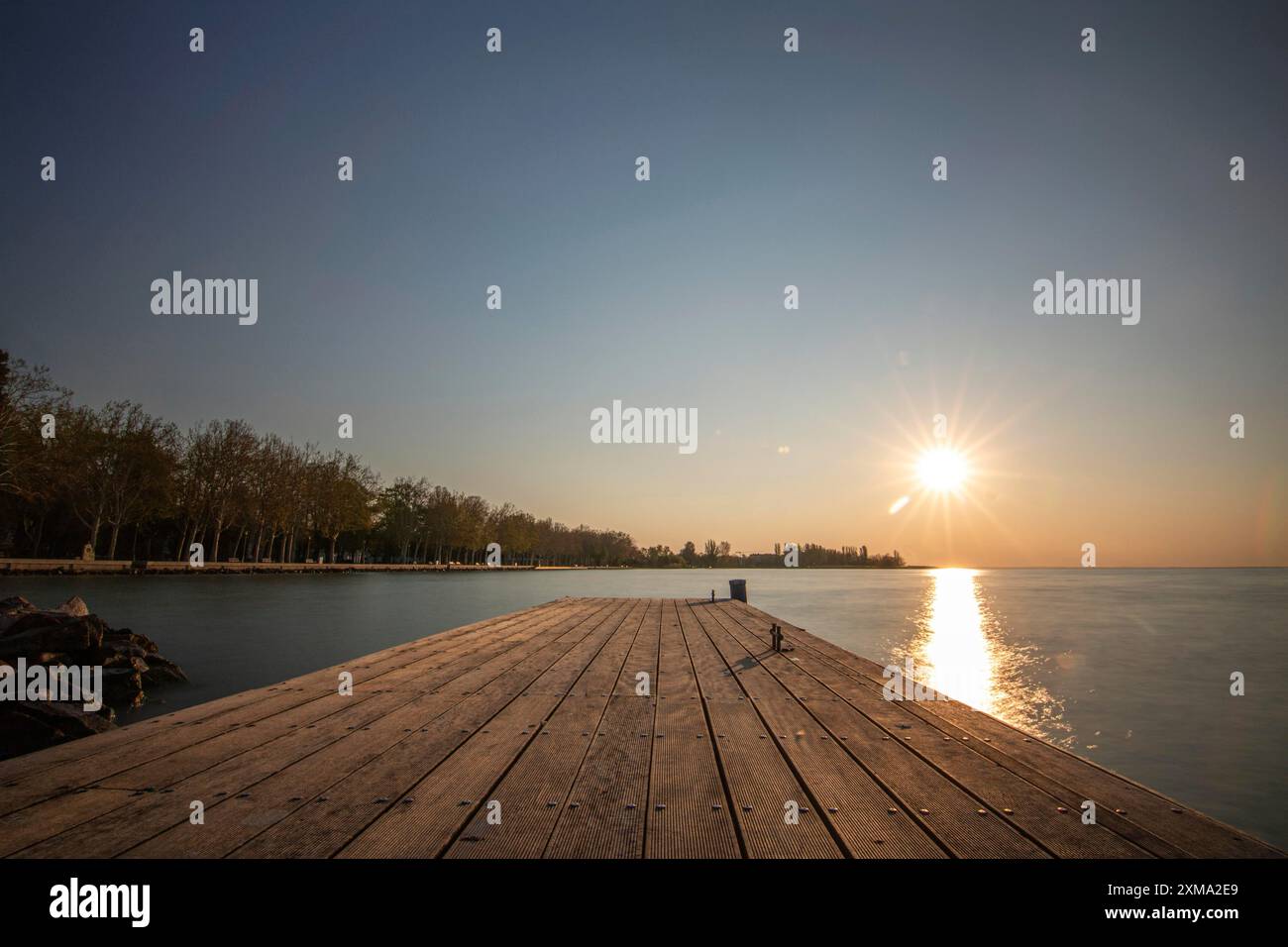 Sunrise on the shore and harbour of a lake in summer. Colourful sky ...