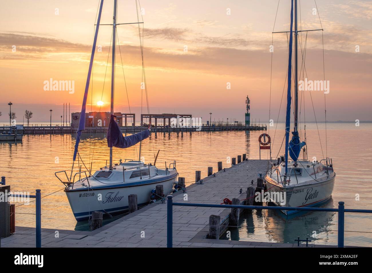 Sunrise on the shore and harbour of a lake in summer. Colourful sky ...