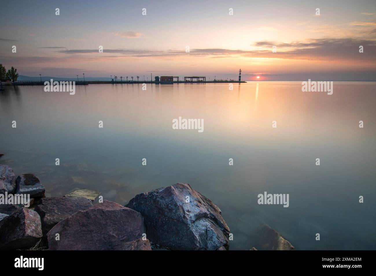 Sunrise on the shore and harbour of a lake in summer. Colourful sky ...