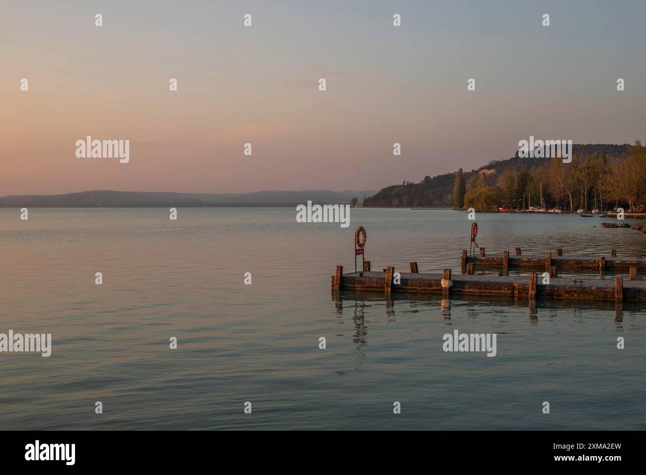 Sunrise on the shore and harbour of a lake in summer. Colourful sky ...